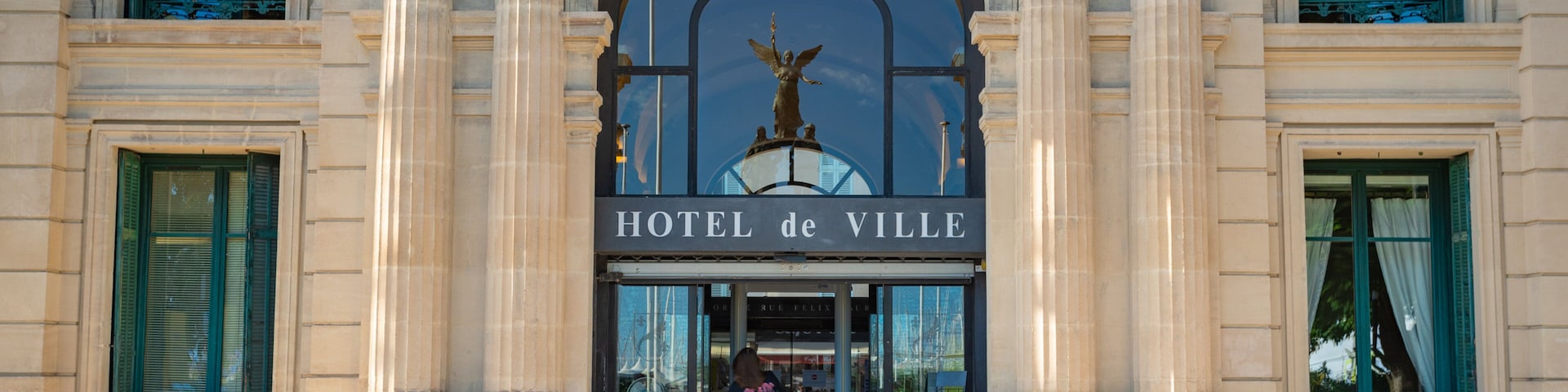 A entrada do HOTEL de VILLE com arquitetura clássica, incluindo colunas e uma estátua.