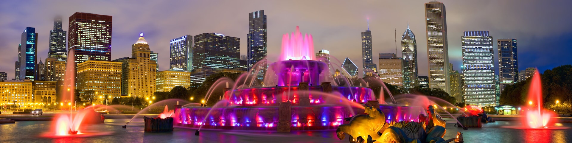 Paisagem urbana com arranha-céus iluminados e um vibrante show de fontes.