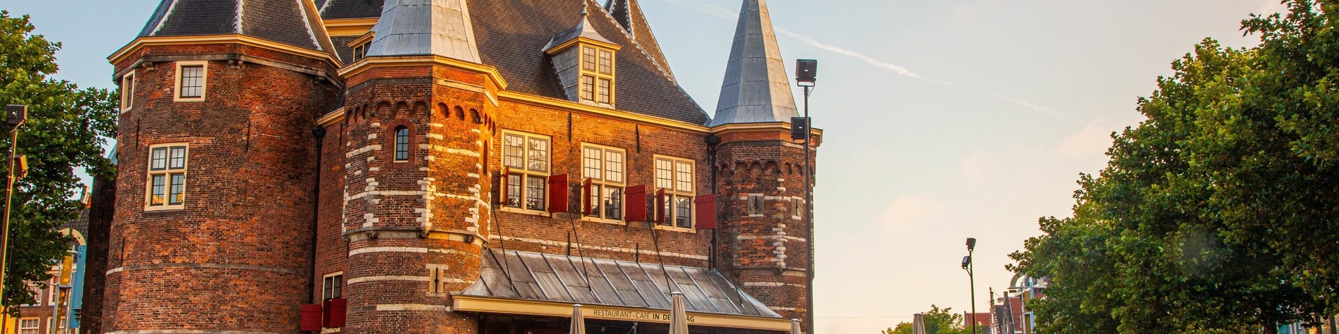 Um edifício histórico com várias torres e um café chamado "Restaurant Café De".