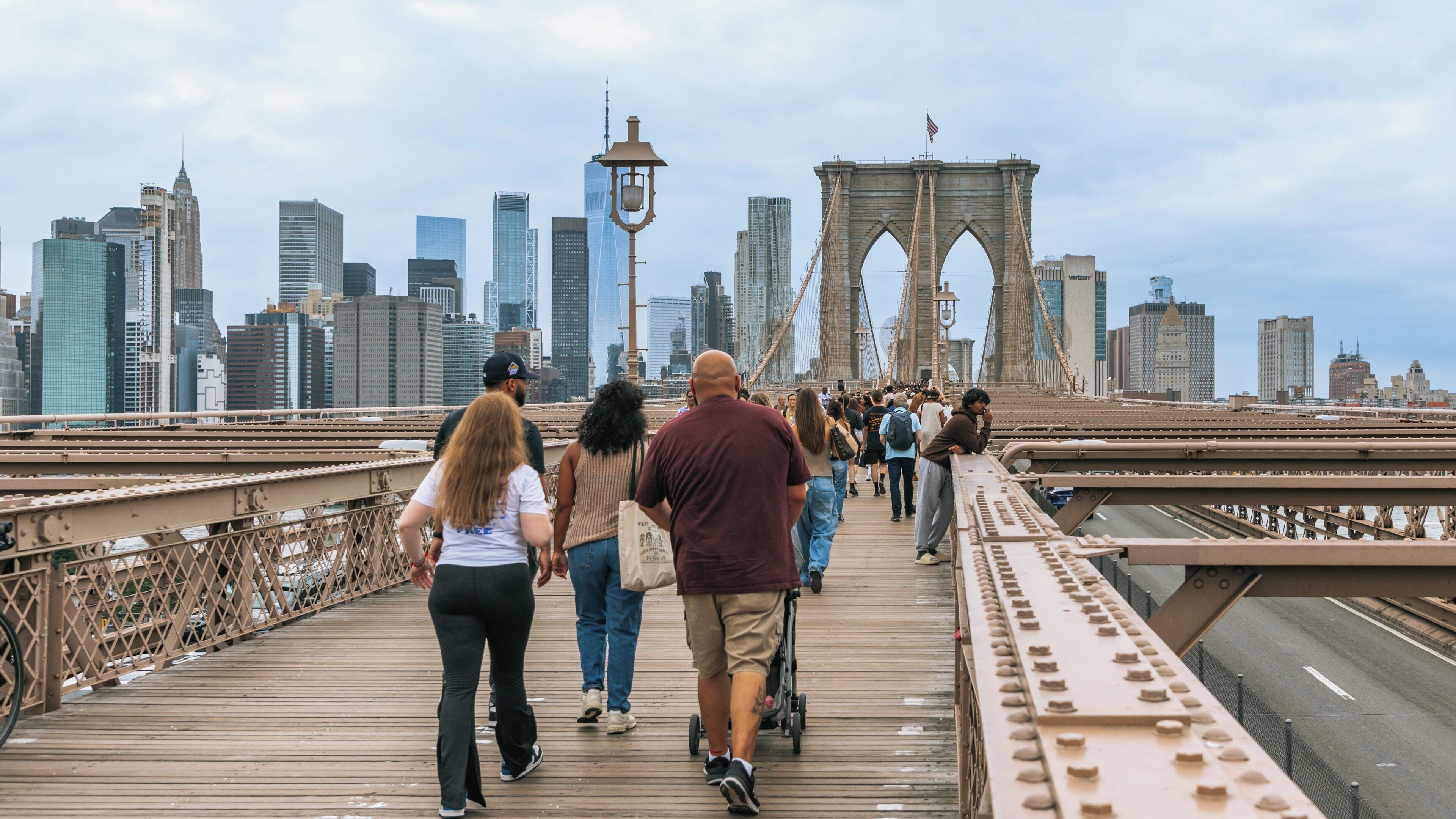 Exploring Brooklyn Bridge against the backdrop of New York City's skyline on a busy day