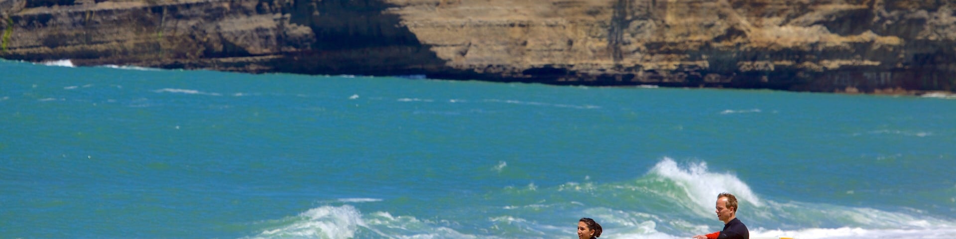 Grand Beach featuring rocky coastline, surfing and a sandy beach