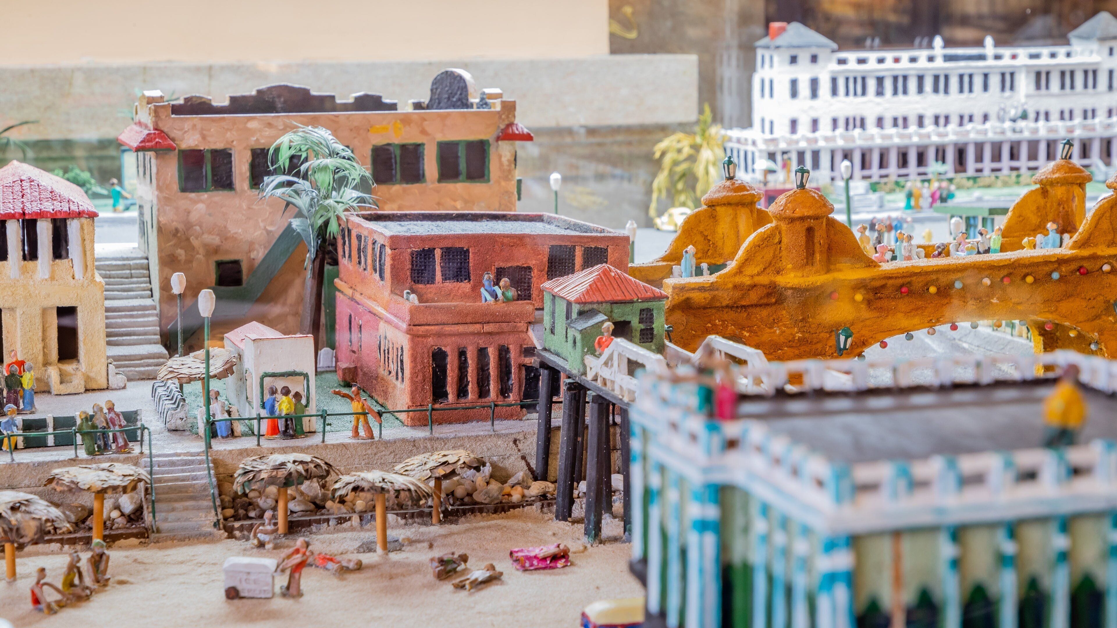Um modelo detalhado de uma cidade histórica, com edifícios em miniatura, figuras e uma ponte.