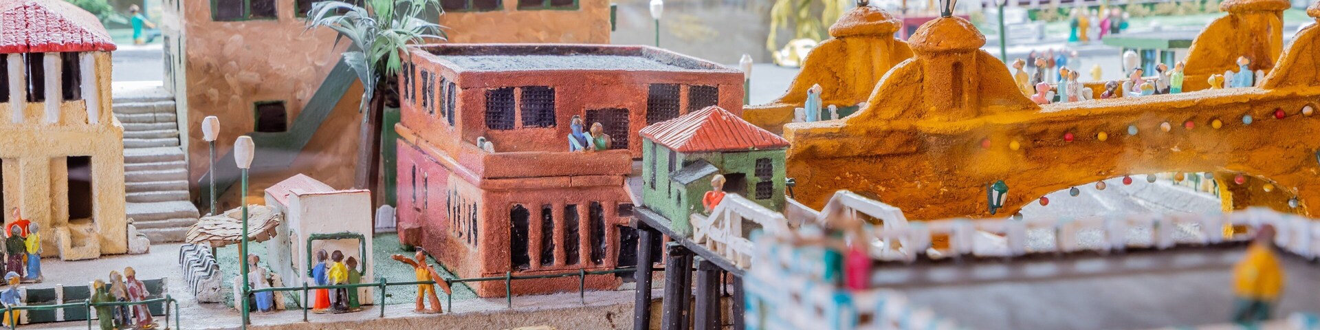 Um modelo detalhado de uma cidade histórica, com edifícios em miniatura, figuras e uma ponte.