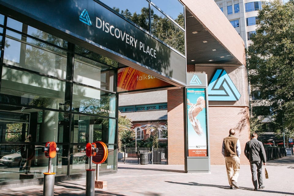 Um edifício moderno com fachada de vidro e uma placa com a inscrição 'DISCOVERY PLACE'.