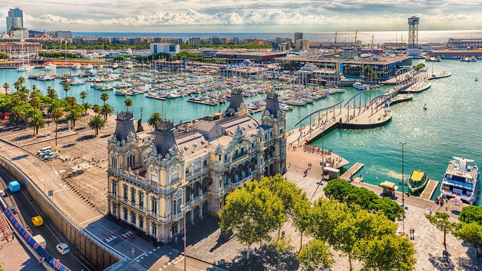 Uma marina com muitos barcos, um edifício histórico e uma orla marítima.
