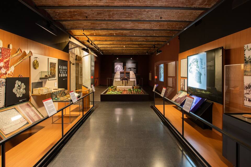 Exposição em museu com artefatos históricos, documentos e painéis informativos.