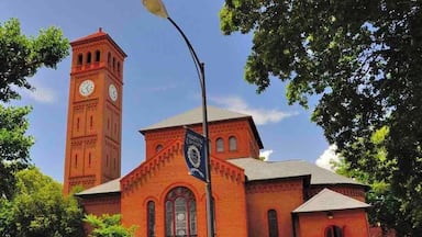 Uma igreja de tijolos vermelhos com uma torre do relógio e uma bandeira.