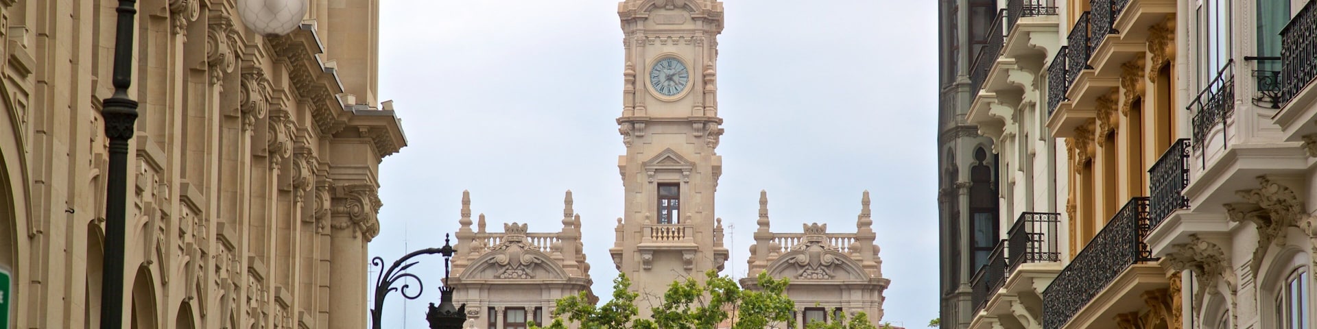 Um edifício histórico com uma torre do relógio, varandas ornamentadas e arquitetura clássica.
