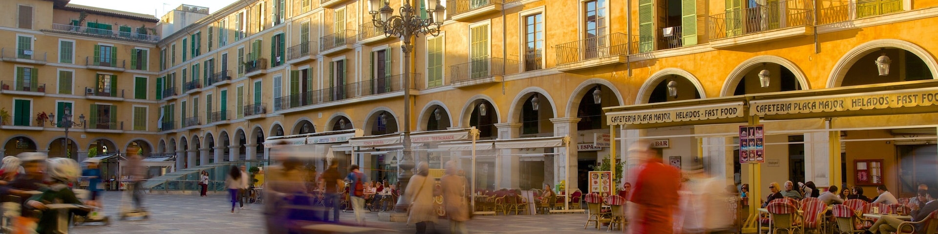 Uma praça movimentada com edifícios históricos, cafés ao ar livre e pessoas caminhando.