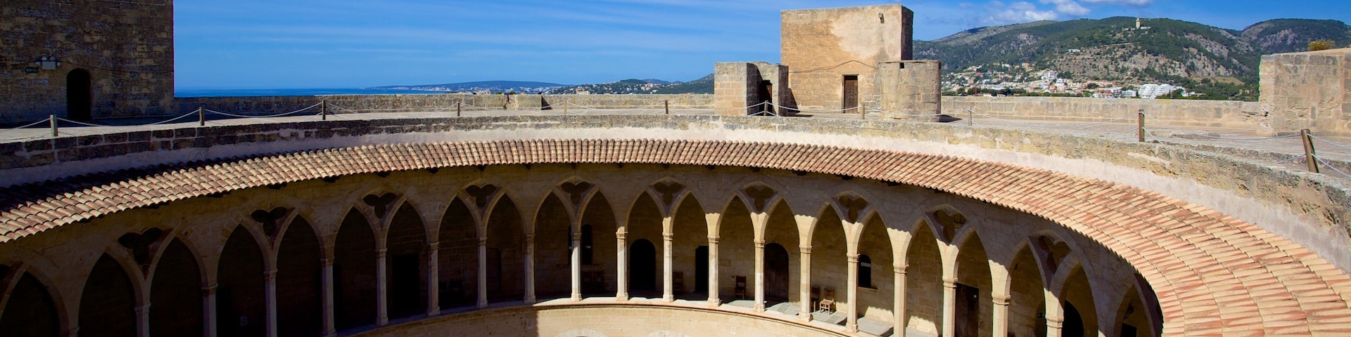 Um anfiteatro histórico com design circular, apresentando múltiplas arcadas e um espaço central aberto.