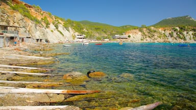 Uma paisagem costeira com águas cristalinas, costa rochosa e edifícios na encosta.