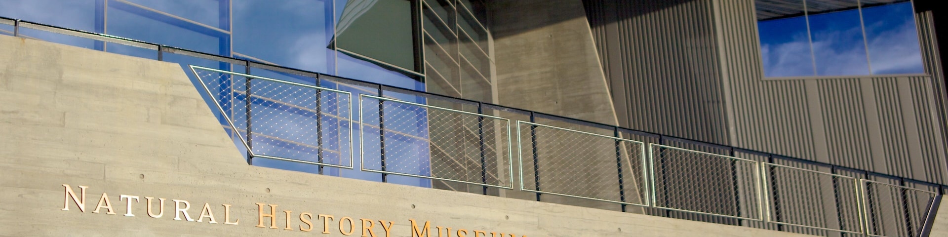 Exterior do Museu de História Natural de Utah, com grandes janelas e um guarda-corpo metálico.