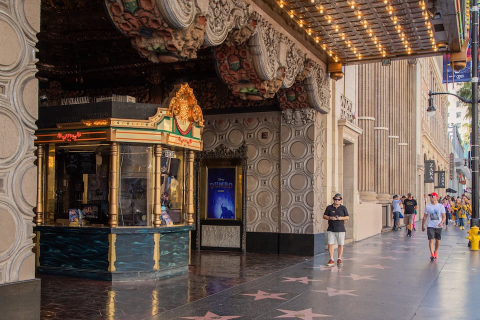 Entrada de teatro com decoração elaborada, letreiro luminoso e calçada com estrelas.
