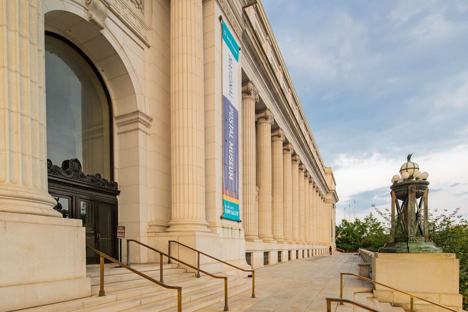 Um edifício imponente com colunas grandes e um banner chamativo do Museu Nacional dos Correios.