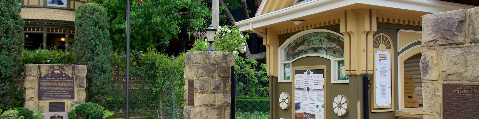 Uma casa histórica com entrada de pedra, uma bandeira e um letreiro de boas-vindas.