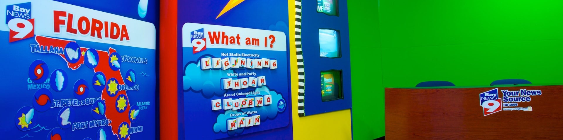 Uma estação meteorológica colorida com um mapa da Flórida, um display interativo 'O que sou eu?' e o logotipo da Bay News 9.