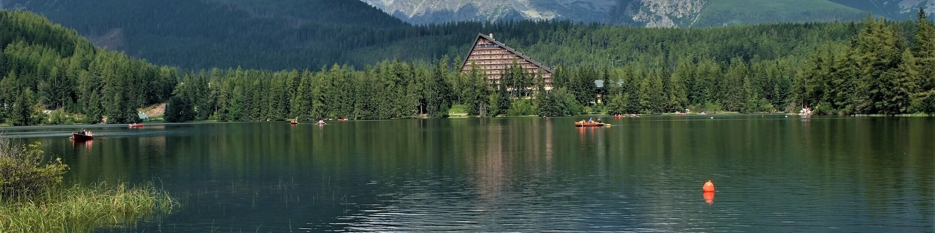 Paisagem montanhosa com uma casa perto de um lago.