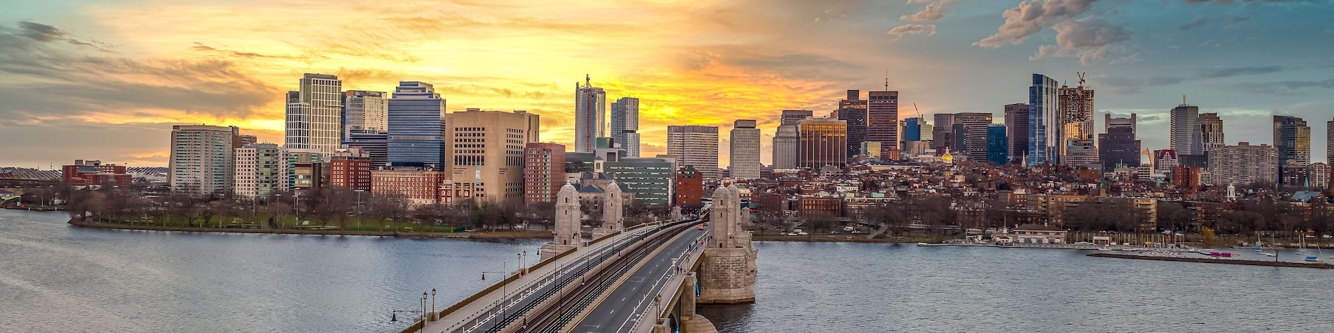 Horizonte urbano com uma ponte sobre um rio ao pôr do sol.