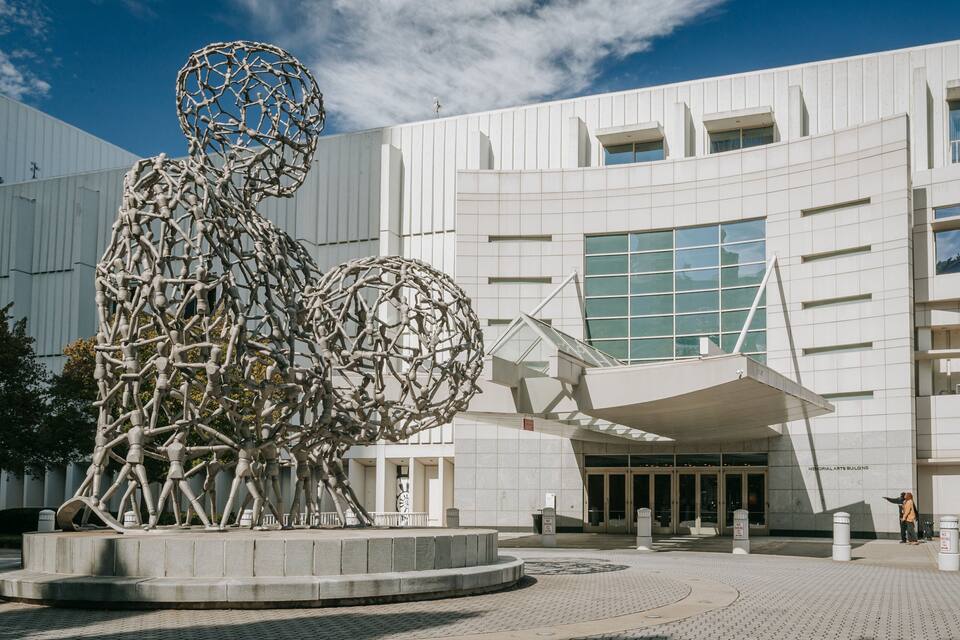 Um edifício moderno com uma escultura única em frente.