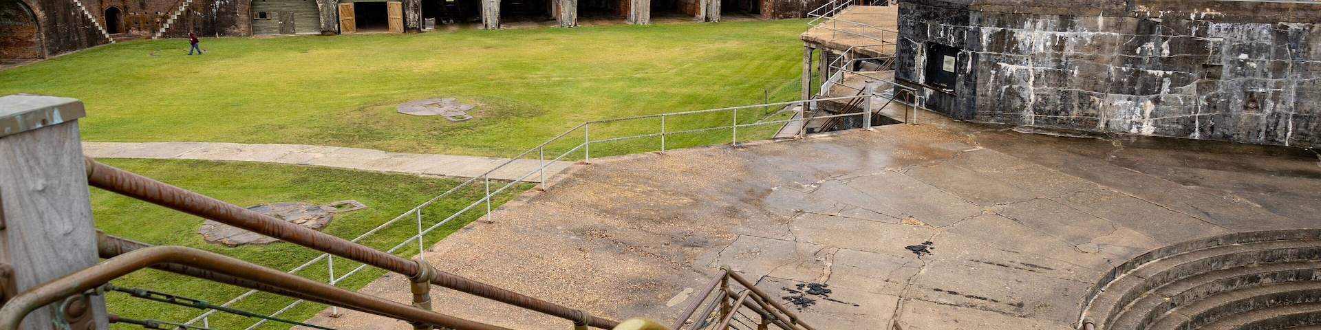 Uma fortaleza histórica com túneis em arco e um pátio gramado.