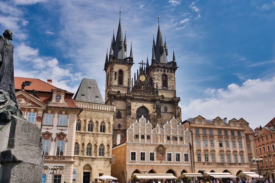 Uma igreja histórica com duas torres e uma estátua em primeiro plano.