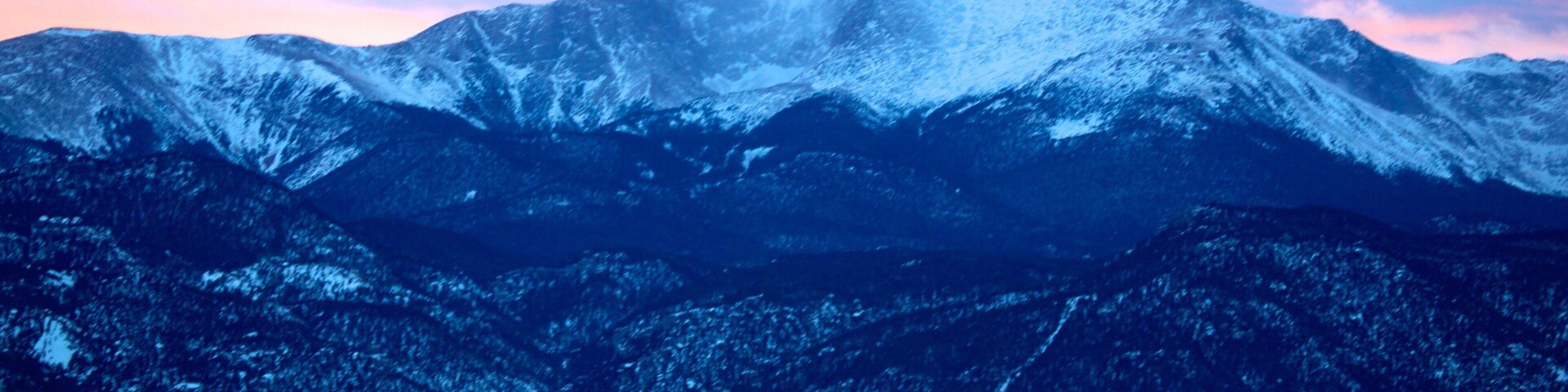 Cordilheira coberta de neve com céu claro.