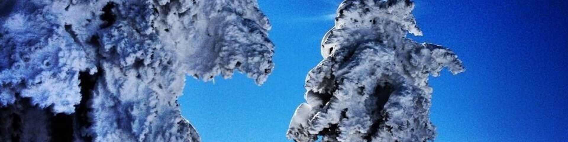 Paisagem de montanha coberta de neve, com formações distintas e um céu azul límpido.