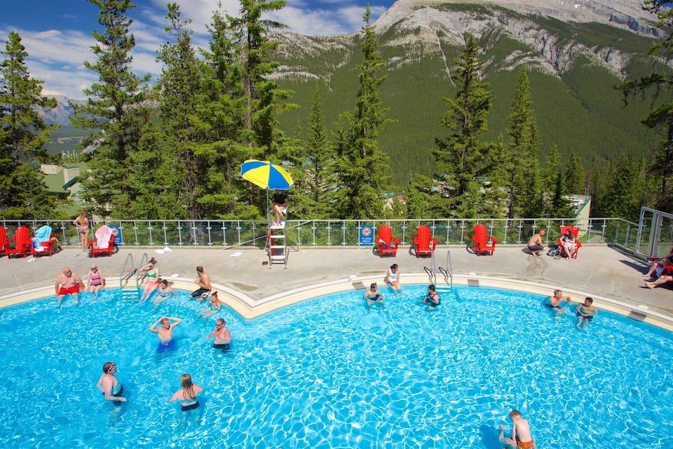 Piscina rodeada por cadeiras vermelhas e um cenário montanhoso.