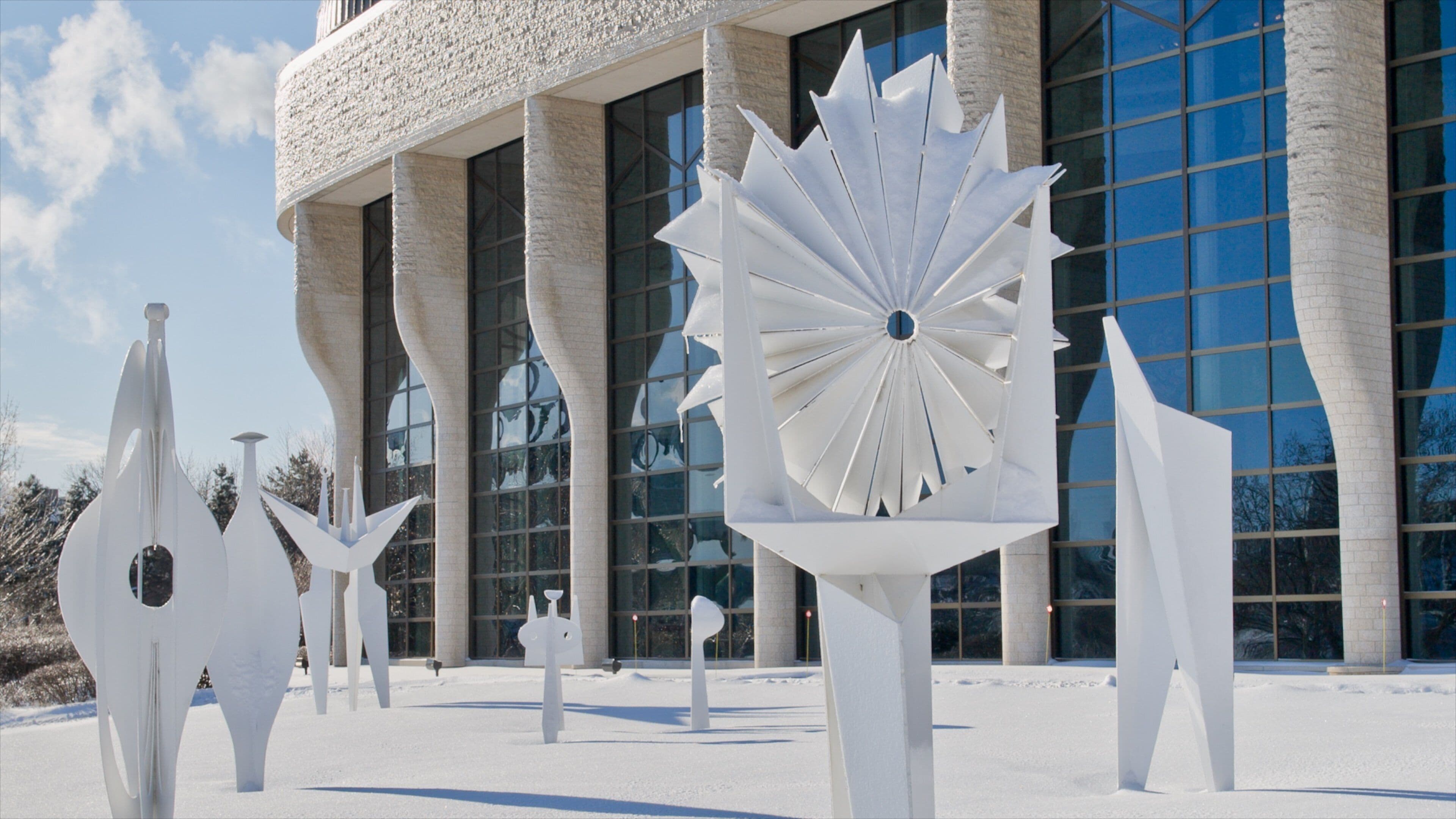Um edifício moderno com janelas amplas e esculturas abstratas em uma paisagem nevada.