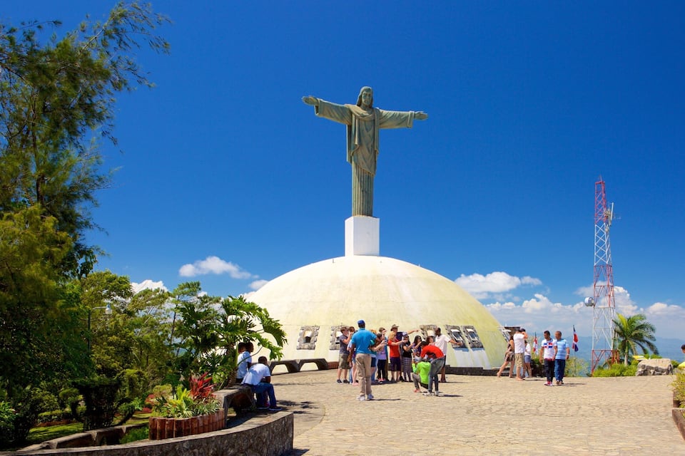 Uma grande estátua com braços estendidos, cercada por uma cúpula e uma multidão de pessoas.