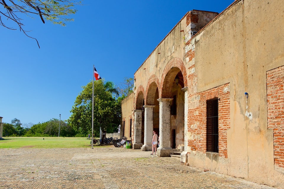 Um edifício histórico com colunas em arco e um mastro.
