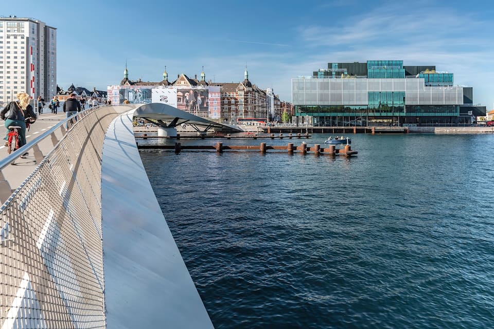 Uma ponte moderna sobre a água, edifícios históricos e um moderno edifício de vidro.
