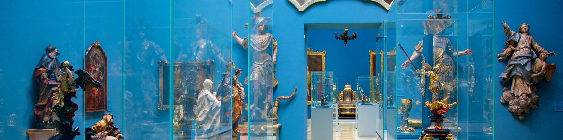 Um museu com vitrines de vidro exibindo esculturas e pinturas.