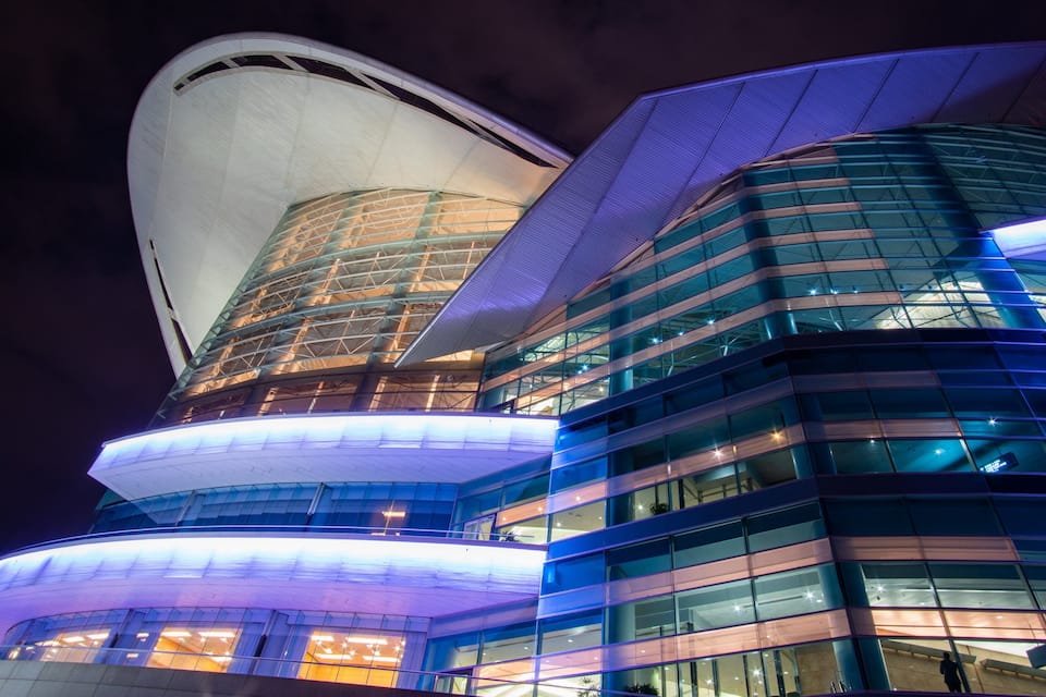 Um edifício de arquitetura moderna com fachada curva e janelas iluminadas à noite.