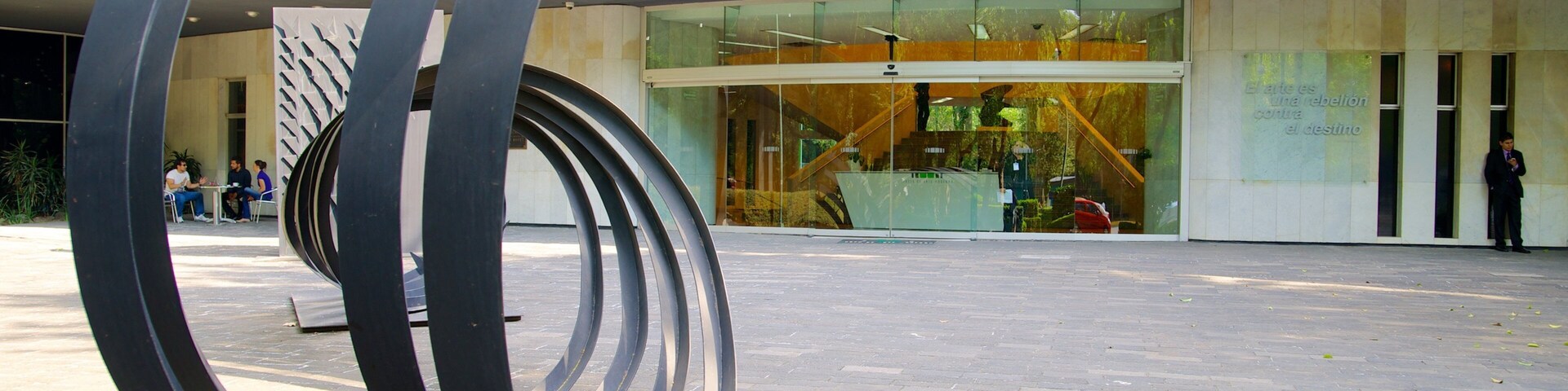 Escultura moderna em frente a um edifício com fachada de vidro e a frase 'Museo de Arte Moderno'.