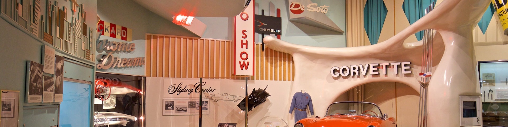 Exposição de carros antigos com um Corvette, rodeado por diversos modelos de automóveis e objetos de coleção.