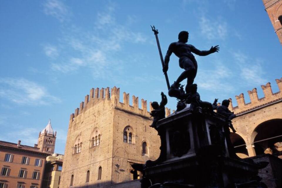 Um edifício histórico com uma torre imponente e uma estátua de uma figura segurando um cajado.