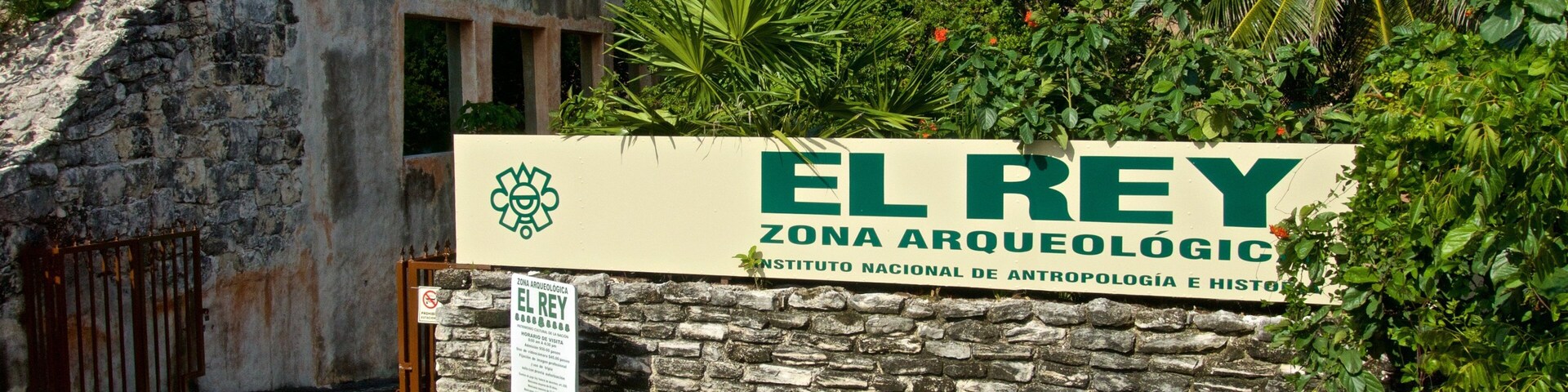 Mural de pedra com uma placa indicando 'El Rey Archaeological Zone' e o logotipo do Instituto Nacional de Antropologia e História.