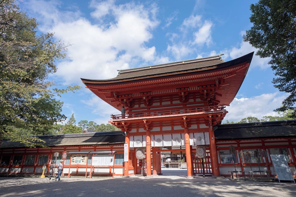Um portão tradicional japonês com telhado vermelho e paredes brancas.