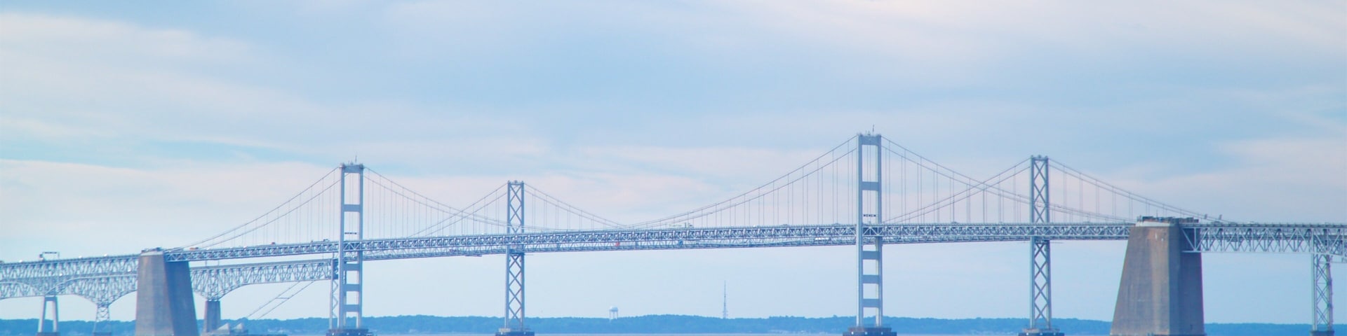 Uma grande ponte suspensa sobre a água, com uma praia arenosa em primeiro plano.