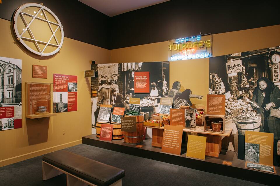 Exposição de museu com fotografias históricas, cartazes informativos e artefatos.