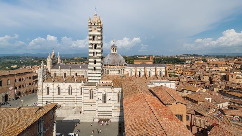 Paisagem urbana histórica com uma torre listrada imponente e uma cúpula grande.