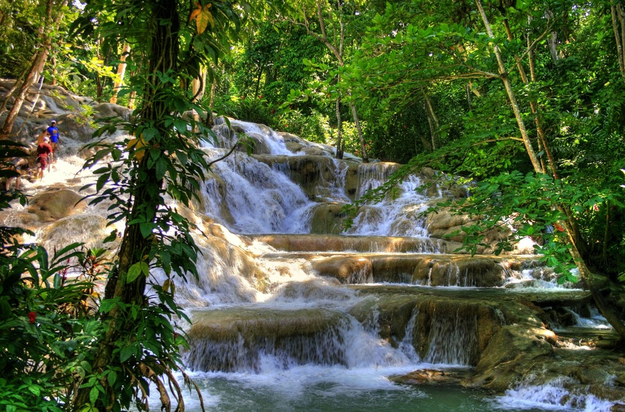 Uma cascata em vários níveis, rodeada por vegetação verde densa.