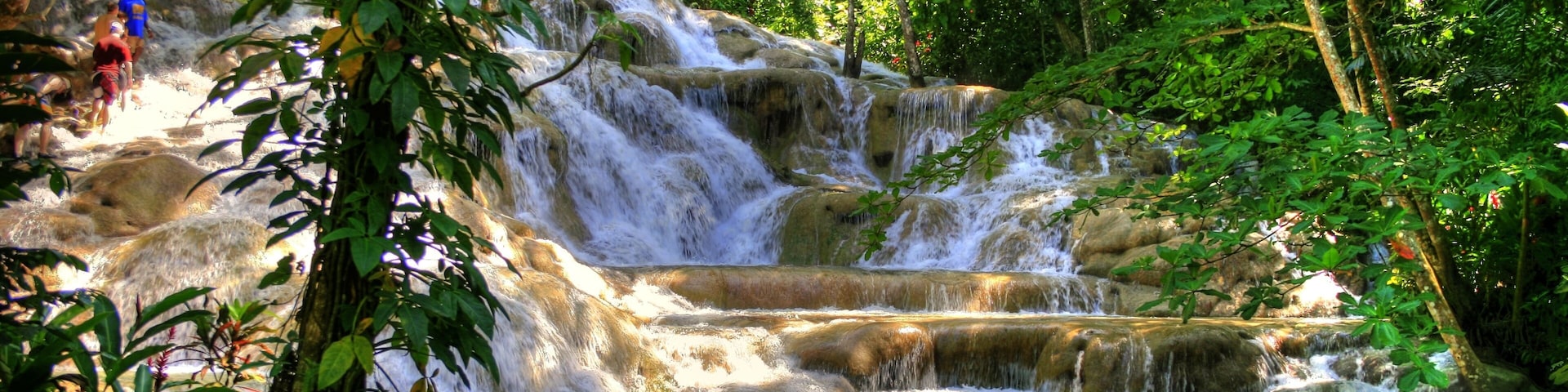 Uma cascata em vários níveis, rodeada por vegetação verde densa.