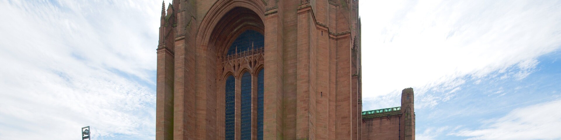 Uma grande catedral de tijolos vermelhos com uma entrada em arco alta e esculturas de pedra elaboradas.
