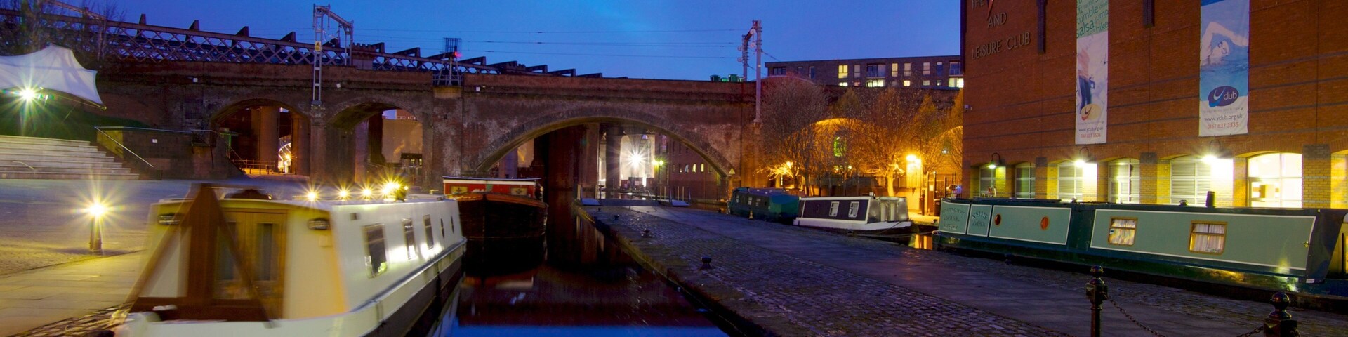 Um canal com barcos, uma ponte e um edifício com um letreiro.