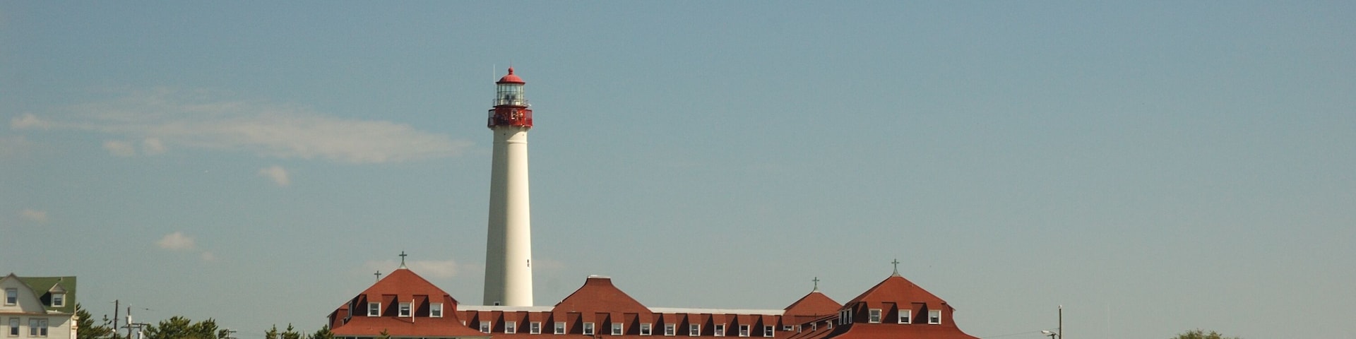 Um edifício costeiro com farol, praia e oceano.