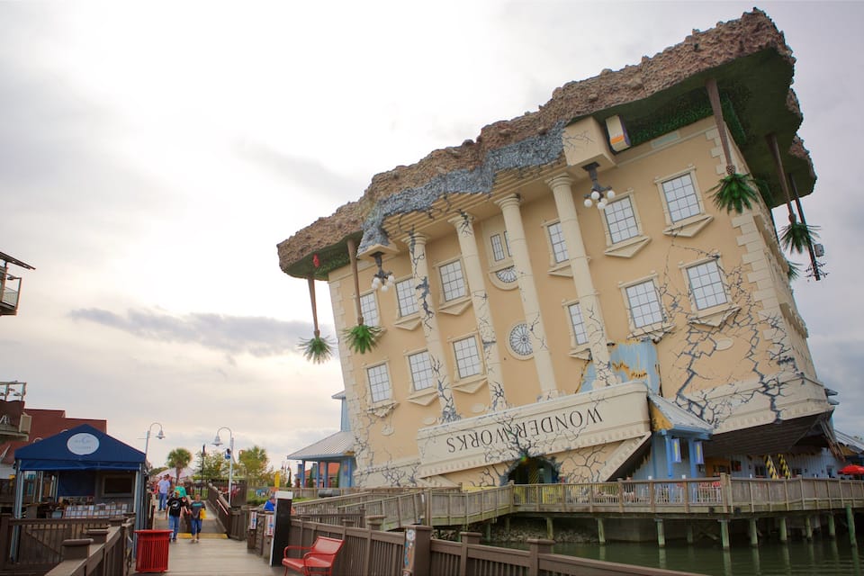 A large building with the words "WONDERS" on its facade, a wooden walkway, and a water body in the foreground.