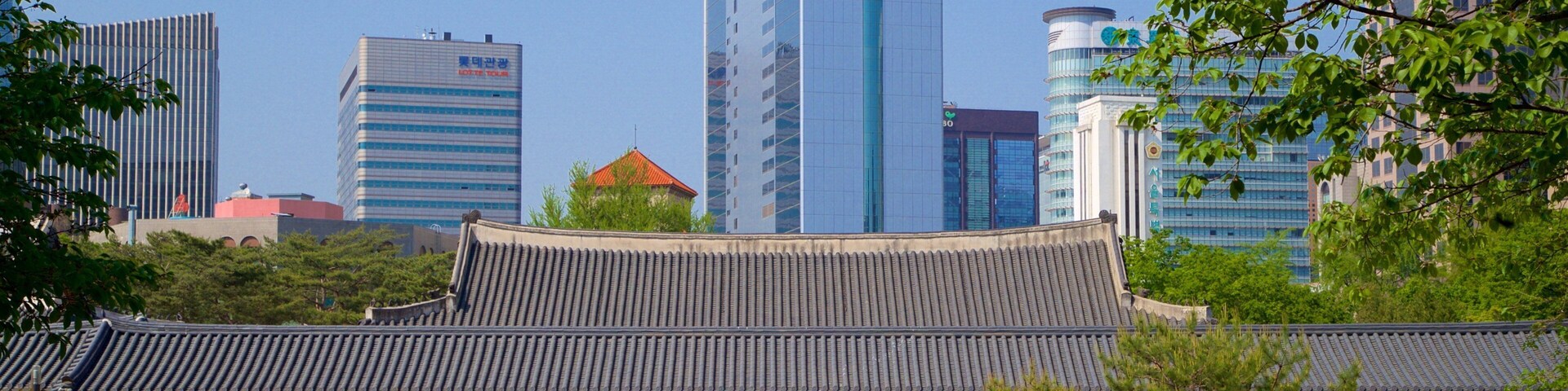 Um edifício coreano tradicional com um arranha-céu moderno ao fundo.
