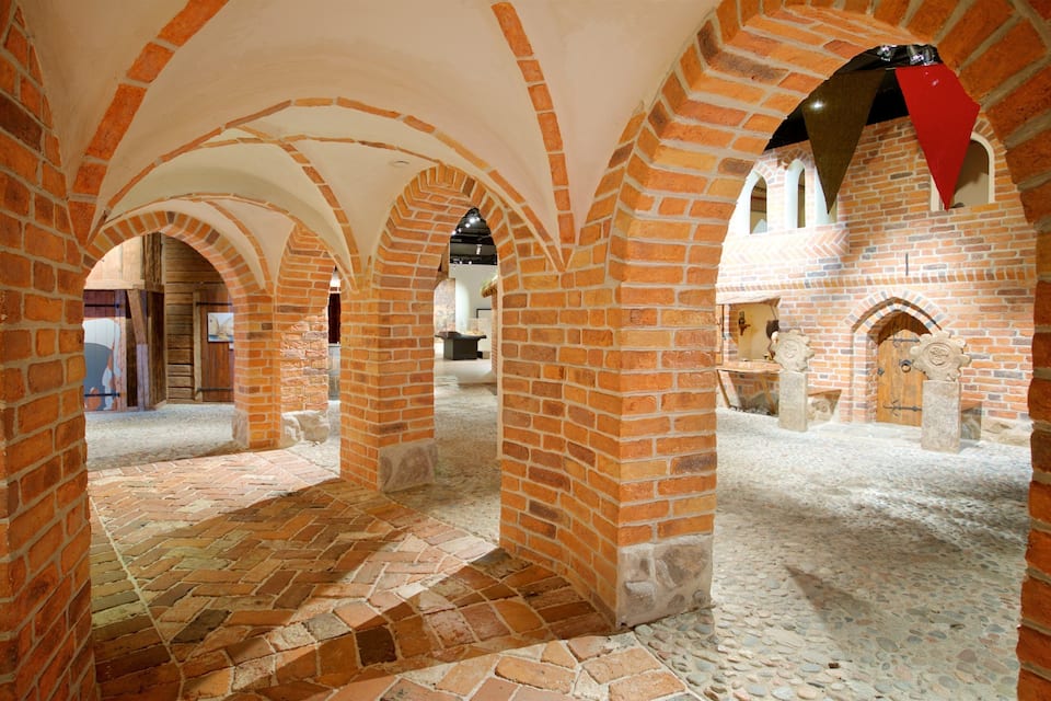 Um corredor de tijolos com arcos e chão de pedras.